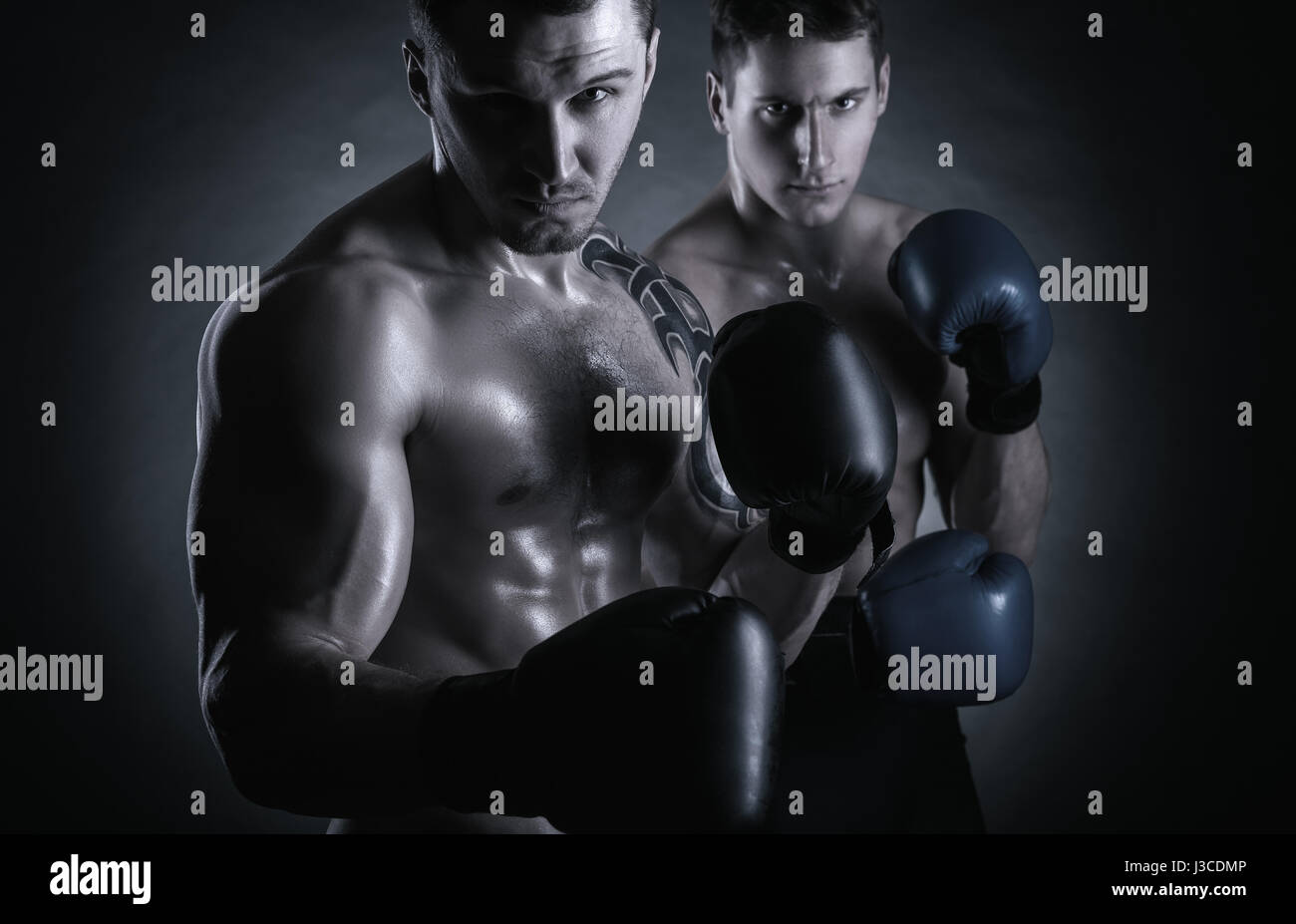 Two young boxer with boxing gloves before a fight on a black background ...