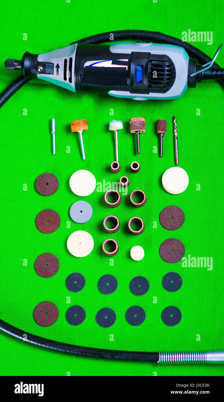 A gray drill with drilling accessories on green background aerial view ...
