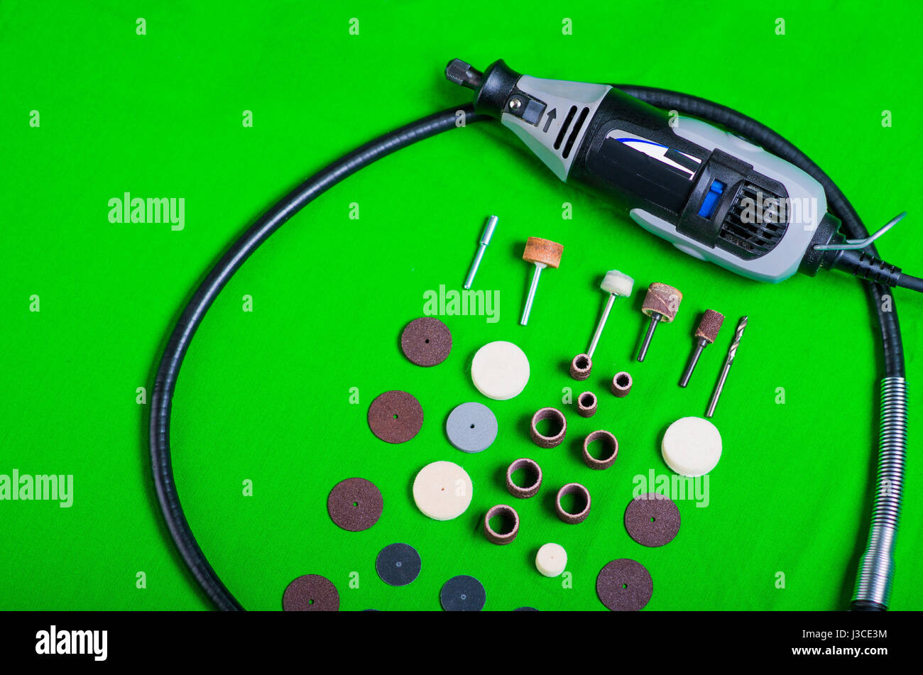 A gray drill with drilling accessories on green background aerial view ...