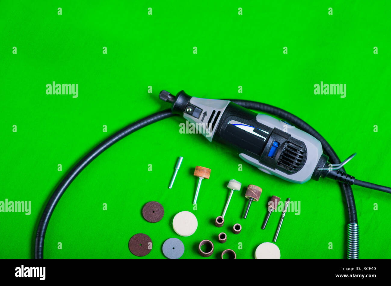 A gray drill with drilling accessories on green background aerial view ...