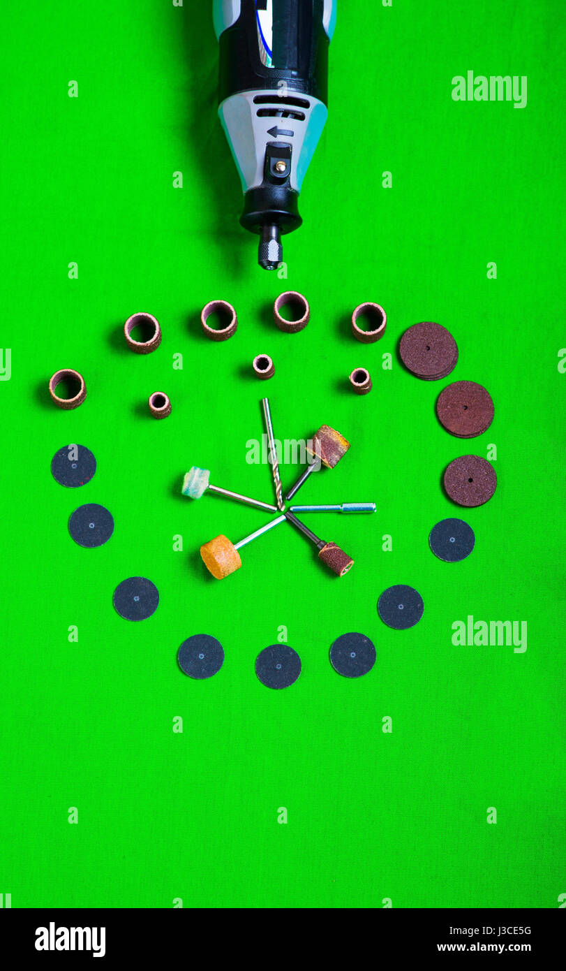 A gray drill with drilling accessories on green background aerial view ...