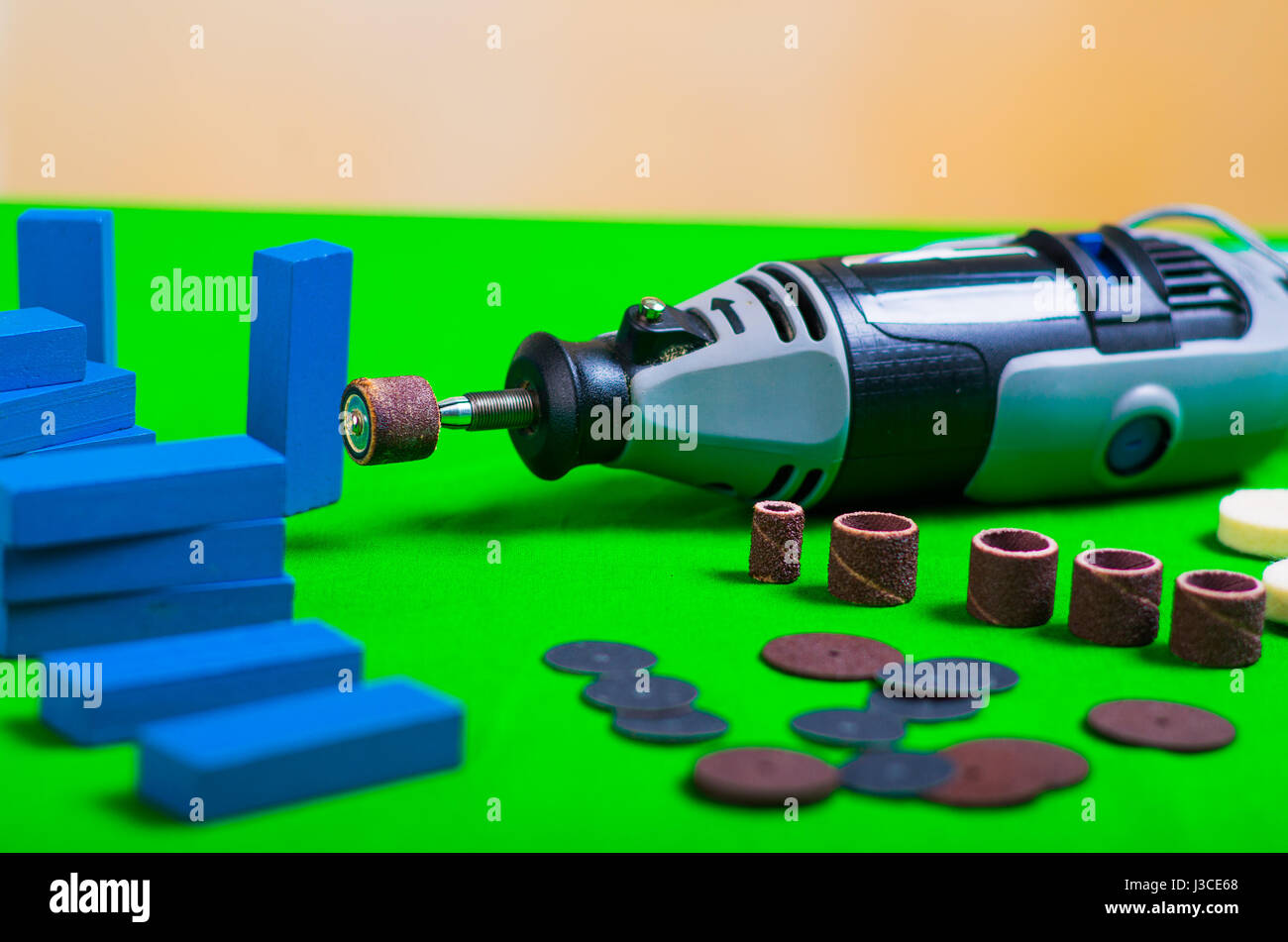 A gray drill with some drilling accessories with a small blue wooden ...