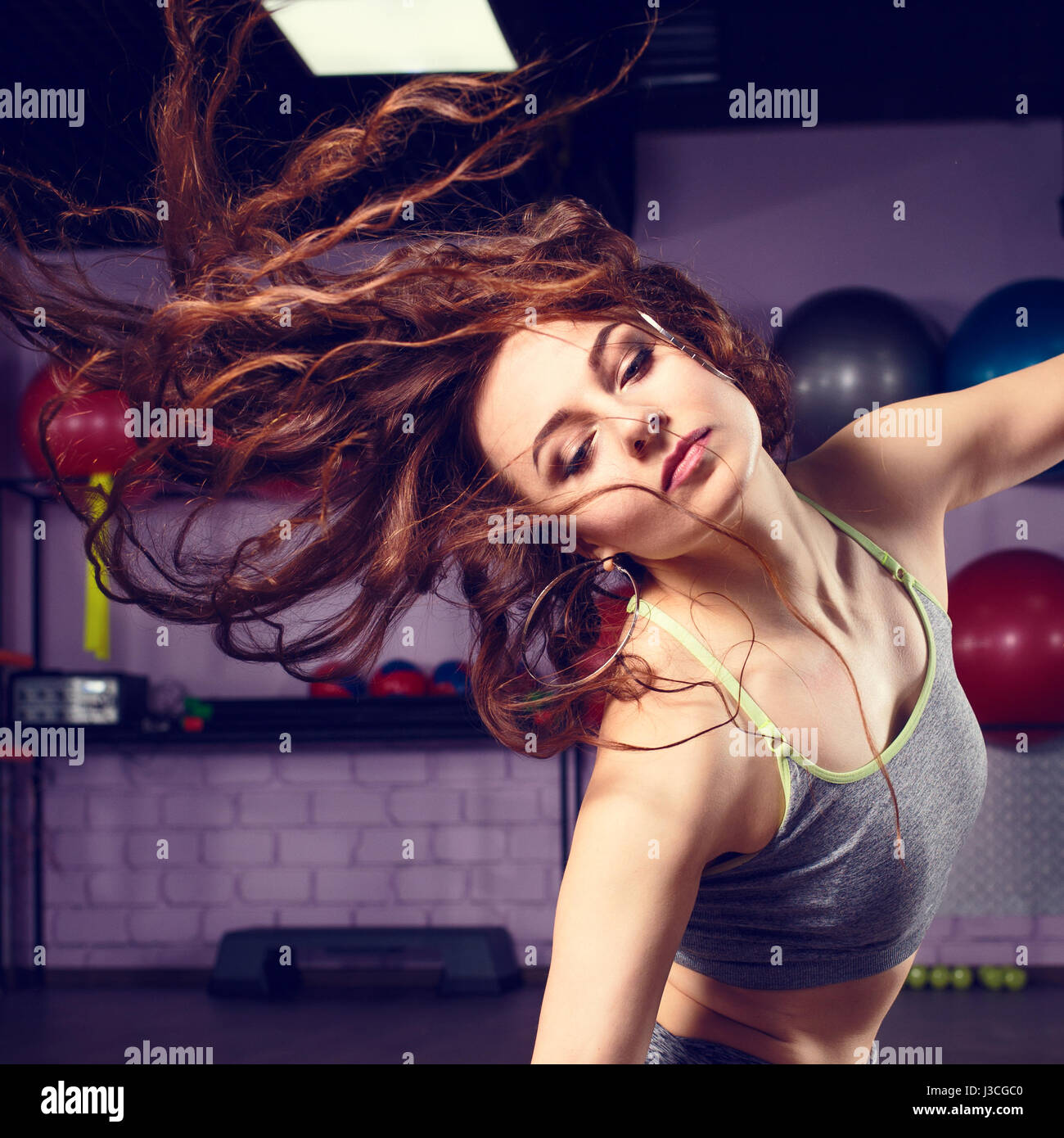 Close up portrait of dancing girl with curly hair in gym. Warm color ...