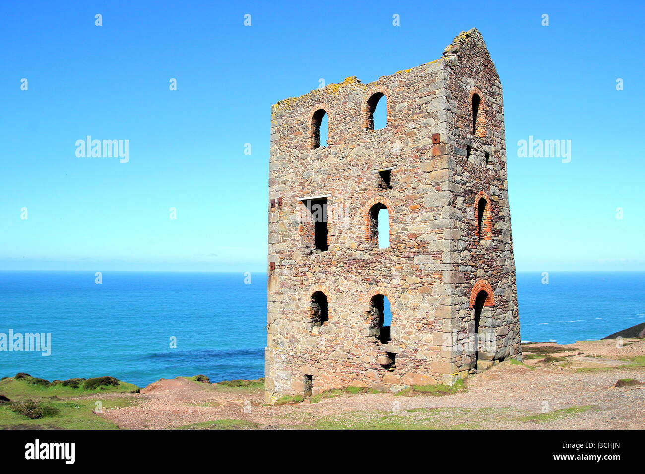 Derelict abandoned Cornish tin mine building on coast path with sea and ...
