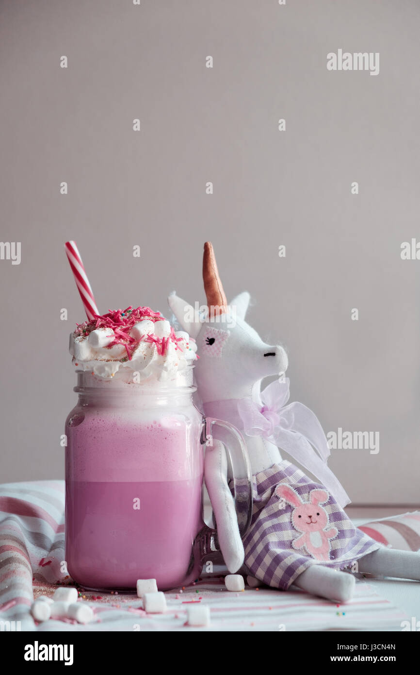 Toy unicorn with pink milk shake with cream, marshmallow and colorful ...