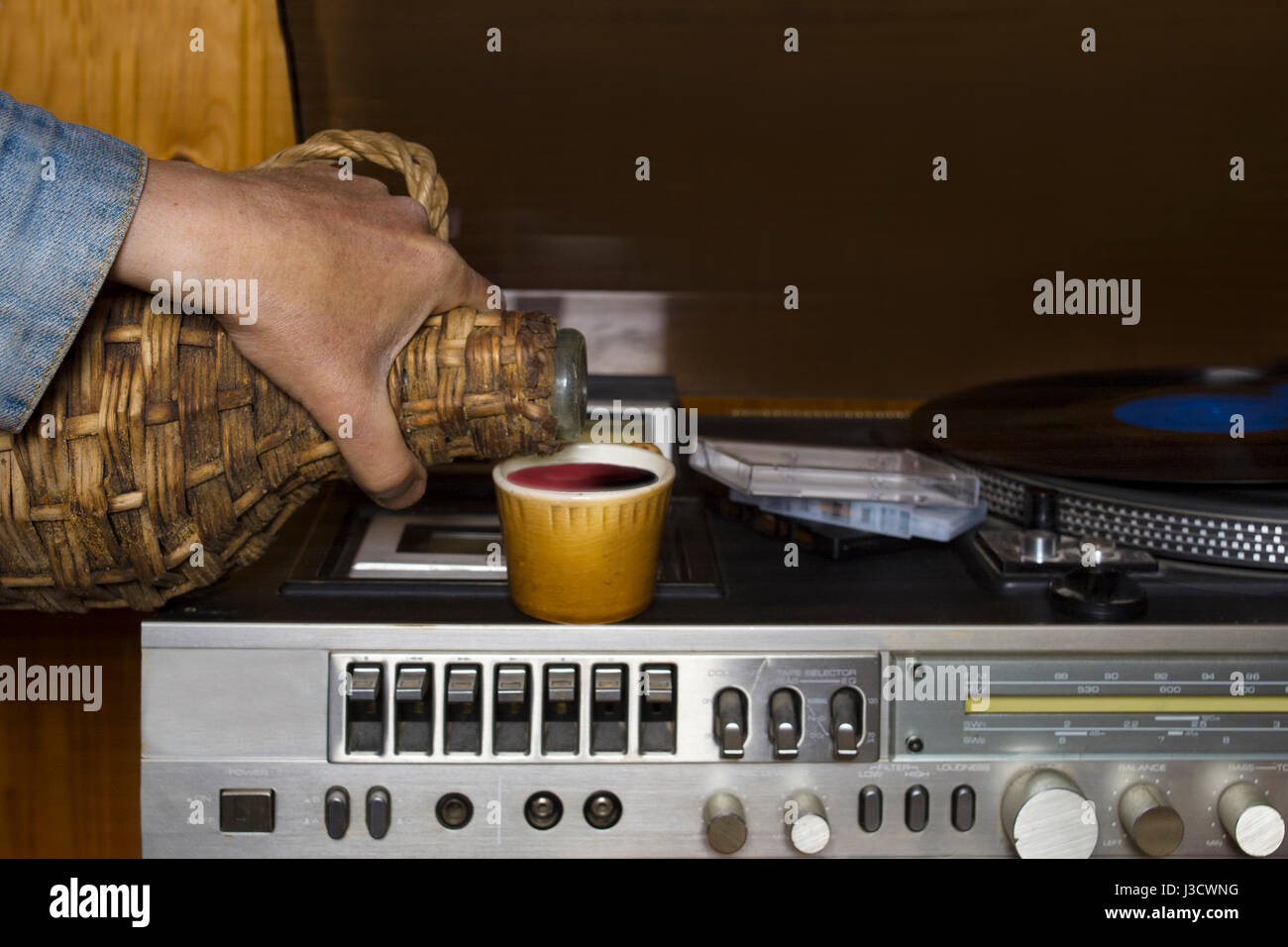 Hand with a bottle of alcohol next to the retro stereo vinyl player ...
