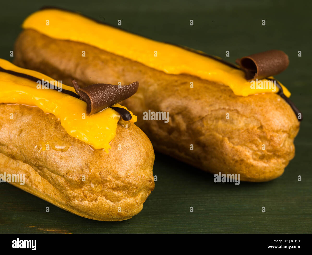 Two Choux Pastry Orange Eclairs Against a Green Backgroound Stock Photo ...