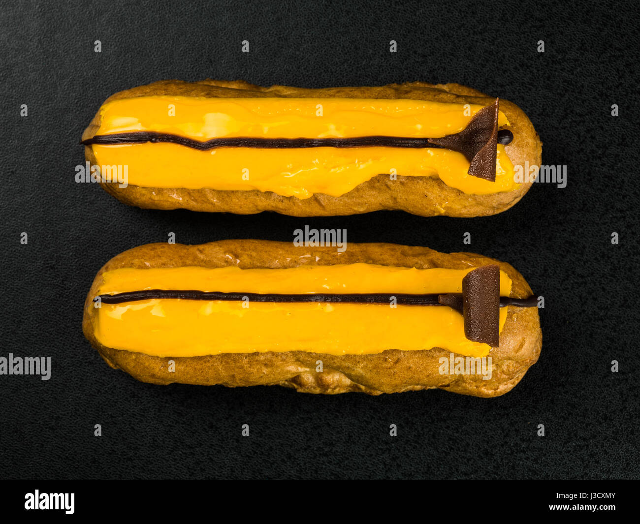 Two Choux Pastry Orange Eclairs Against a Black Background Stock Photo ...