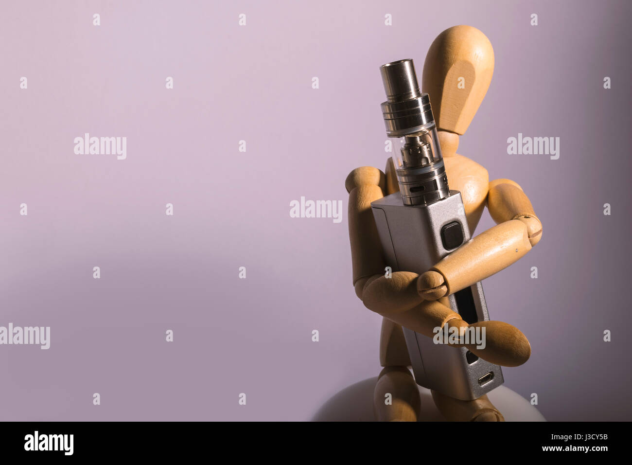 vape device hold by a wooden dummy over a white background Stock Photo ...