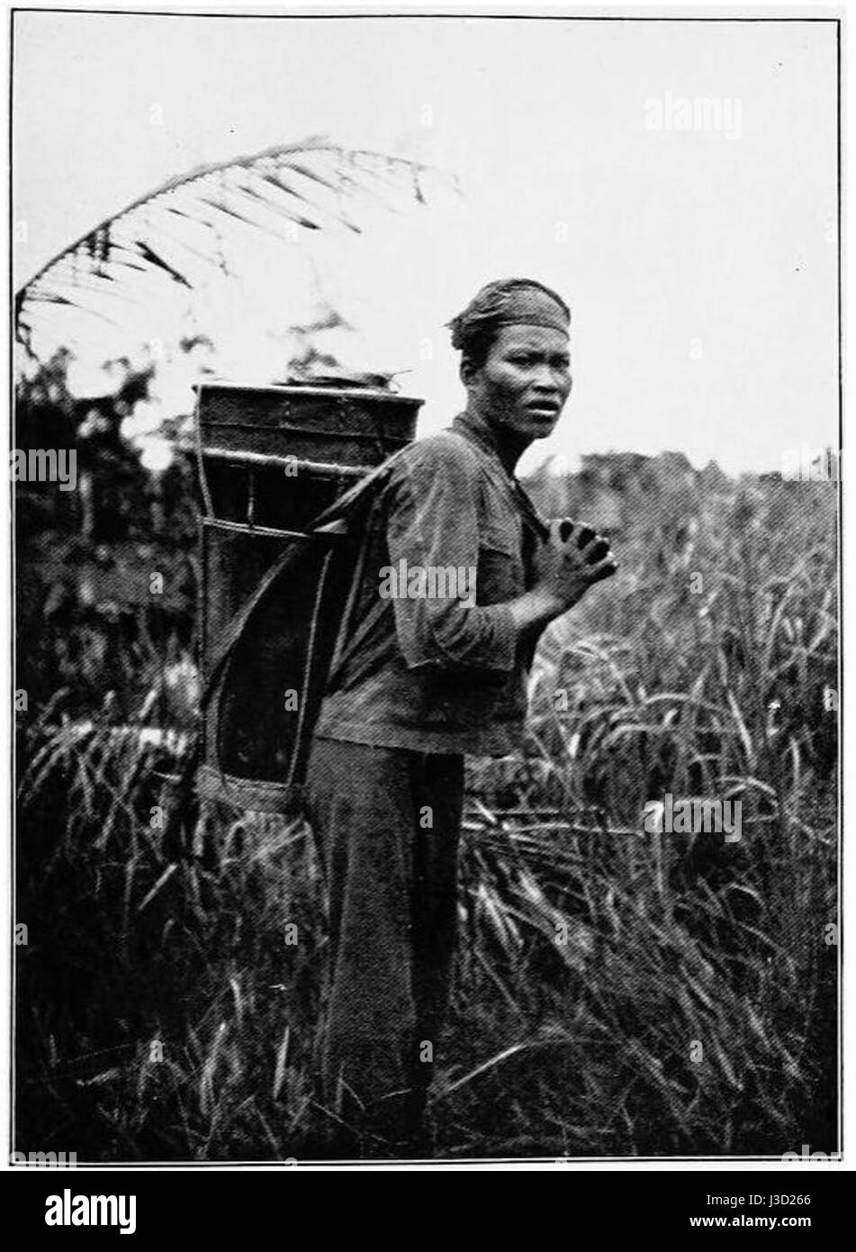 This image depicts a Dusun individual carrying a bongun, a traditional ...