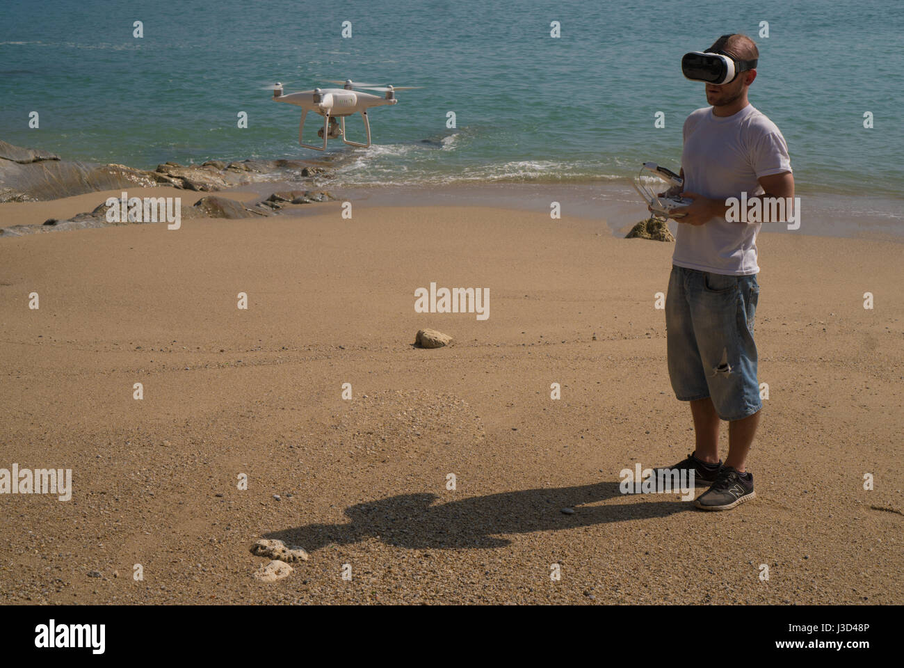 Young man wearing virtual reality glasses standing on the beach with ...