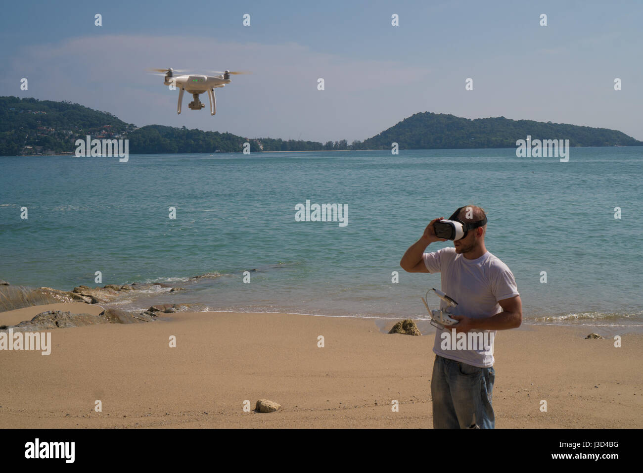 Young man wearing virtual reality glasses standing on the beach with ...