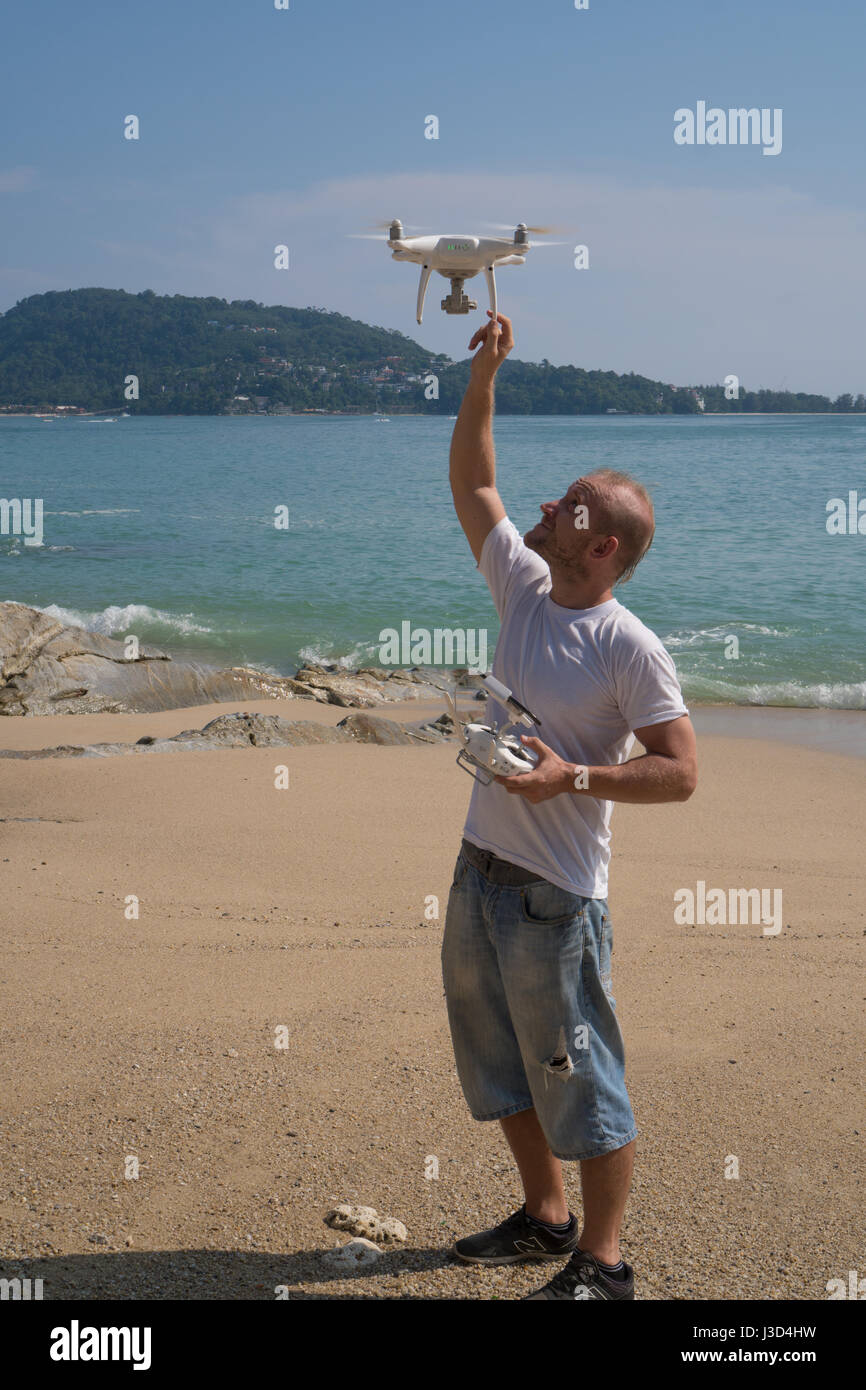 Man catching drone while standing on the beach with remote controller ...