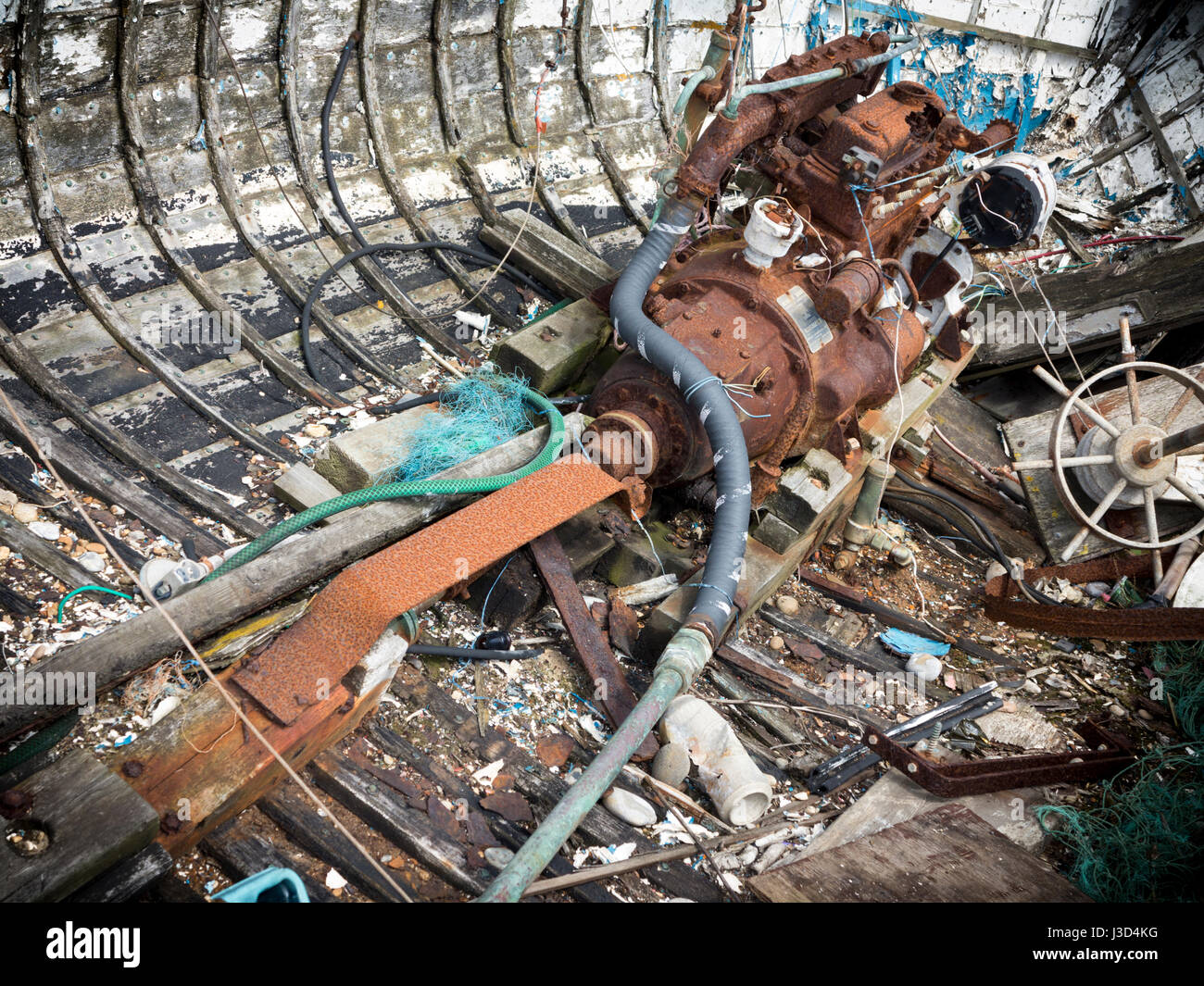 Inside of a derelict wooden boat with rusting engine and other machine ...