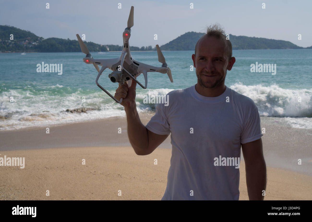 Happy man with drone camera in his hand standing on the beach over ...