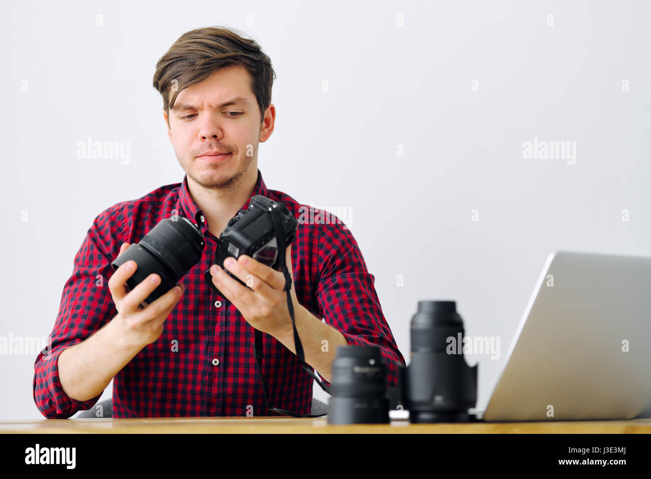 Young guy connects the lens to the camera Stock Photo - Alamy
