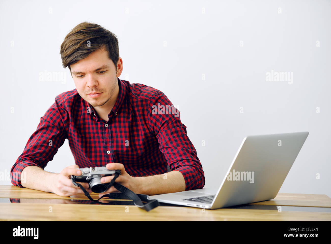 Young and successful man uses Mirrorless camera and sits at a table ...