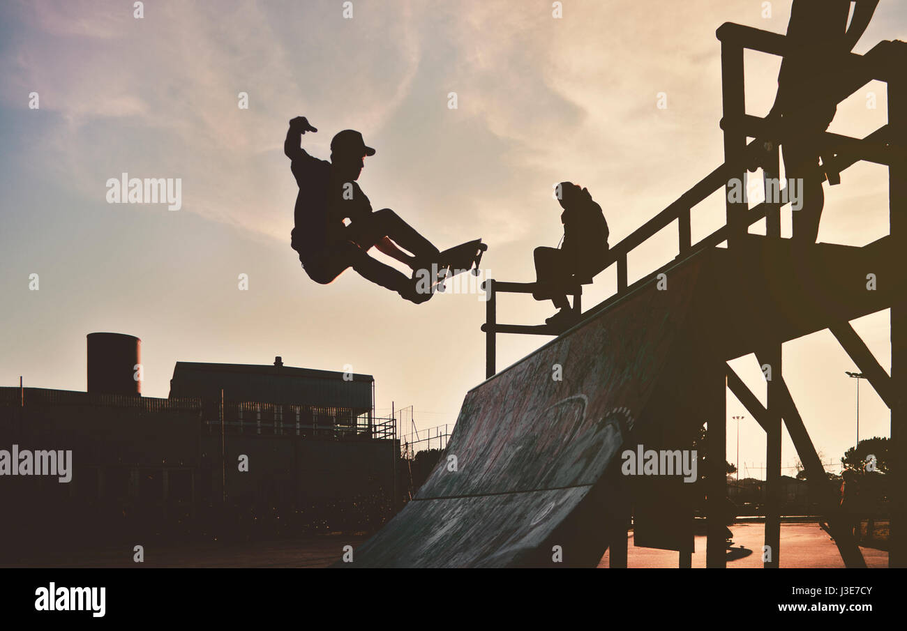 Skateboarder jumping on a ramp. Backlight makes dark silhouettes Stock ...