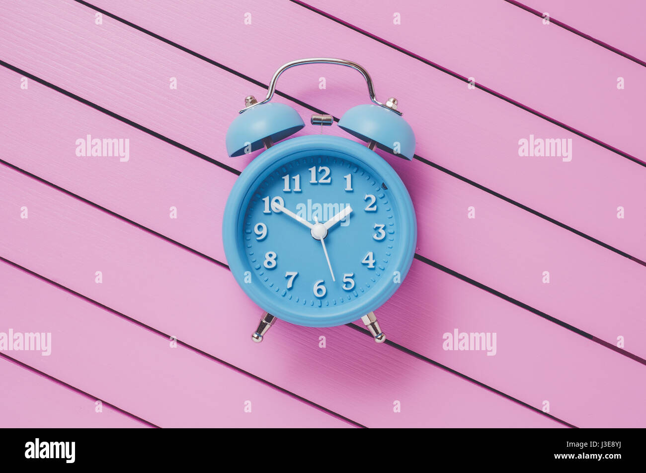 Blue alarm clock on pink wooden background Stock Photo - Alamy