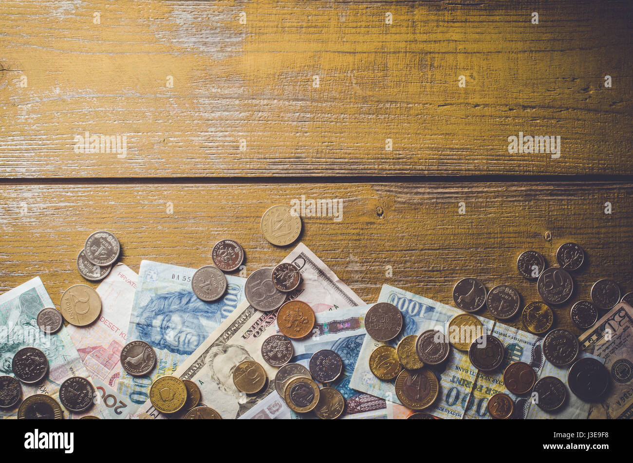 Different banknotes and coins on wooden table Stock Photo - Alamy