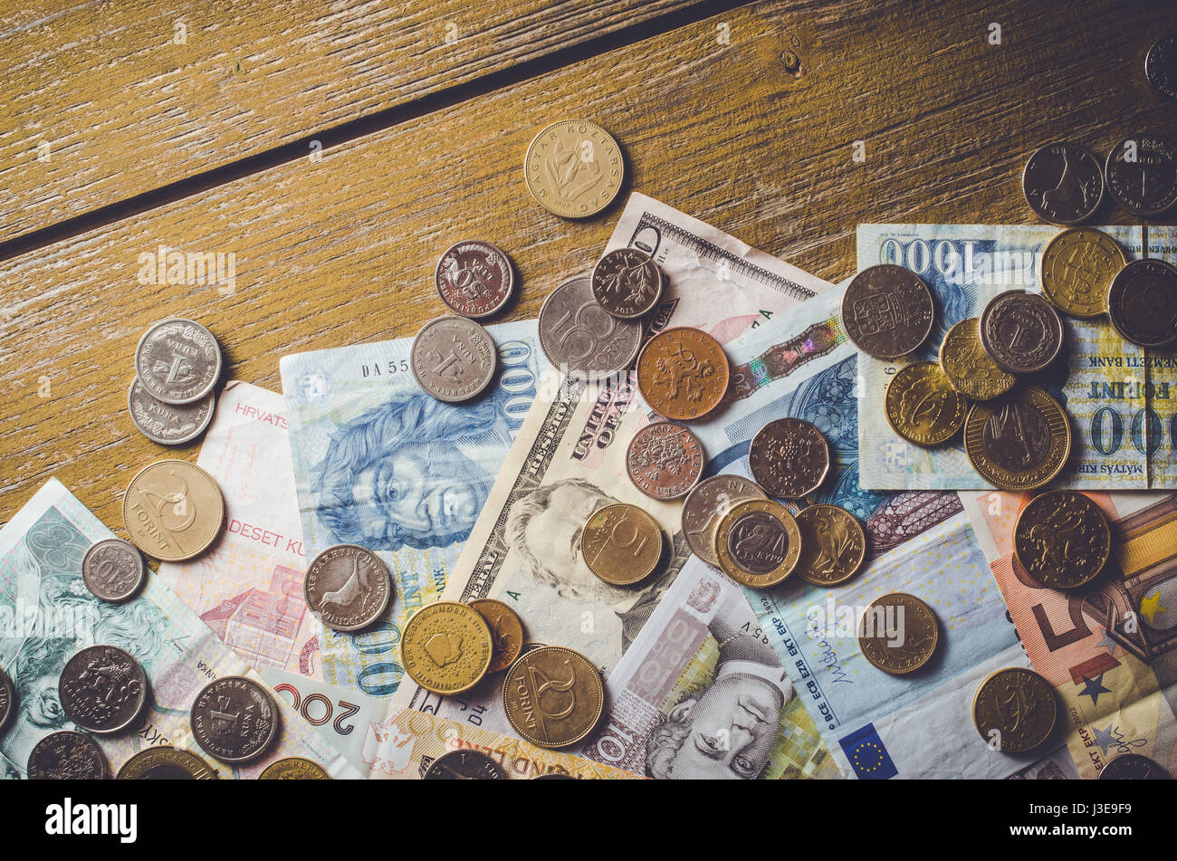 Different banknotes and coins on wooden table Stock Photo - Alamy