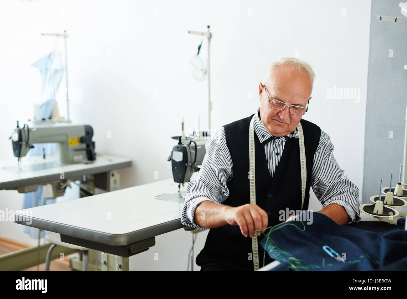 Old Tailor Sewing Garments in Studio Stock Photo - Alamy