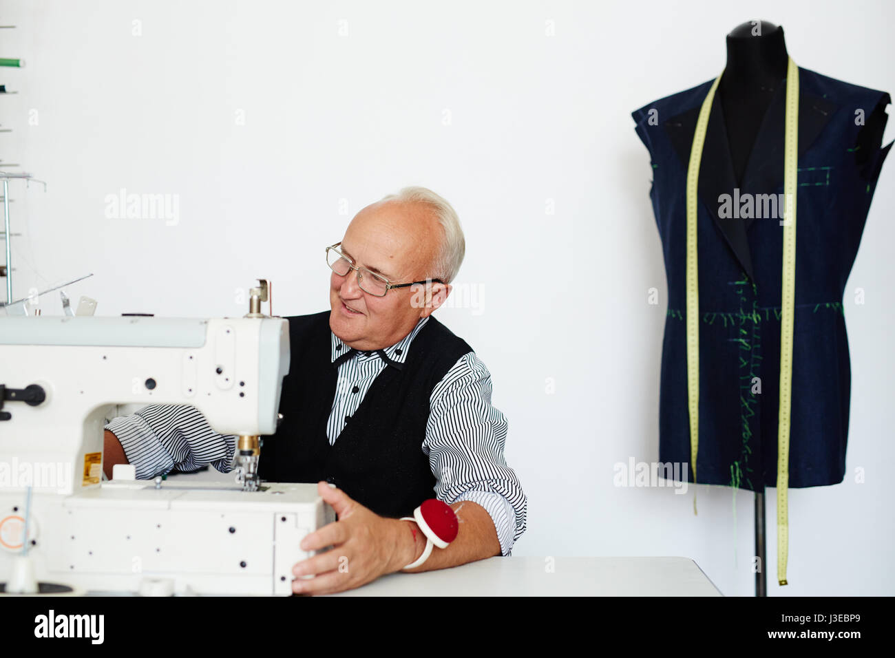 Smiling Old Tailor at Sewing Machine Stock Photo - Alamy