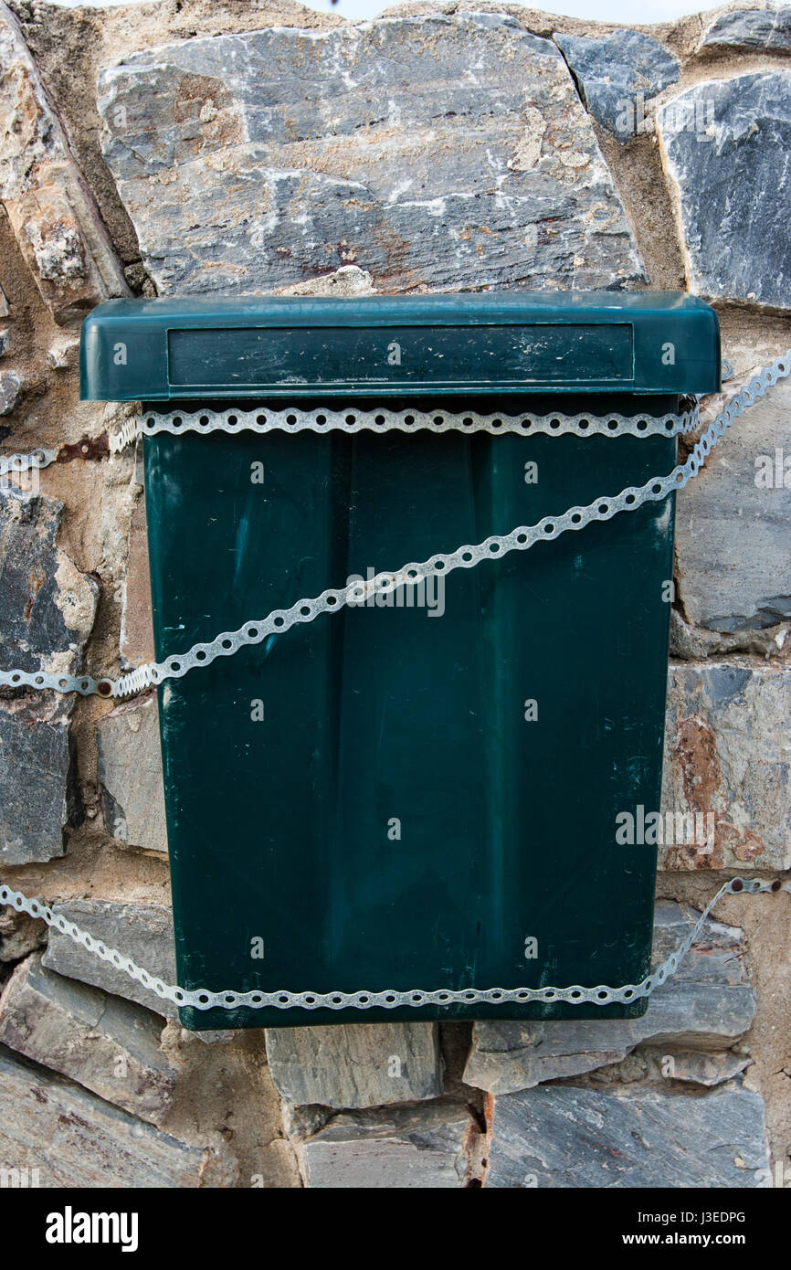 green bin tied to a stone wall Stock Photo - Alamy