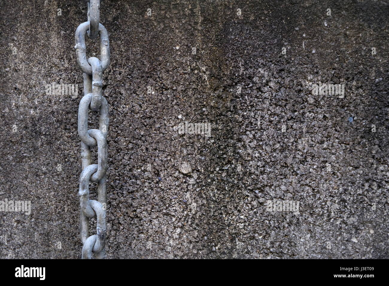 Chain Hanging On A Concrete Wall Background Stock Photo - Alamy