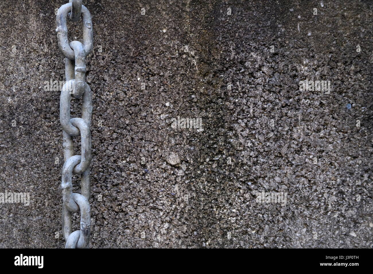 Chain Hanging On A Concrete Wall Background Stock Photo - Alamy