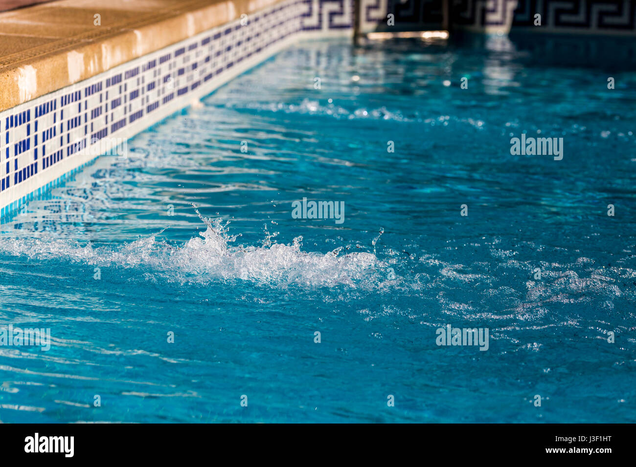 Water jets of a swimming pool with blue tiles Stock Photo - Alamy