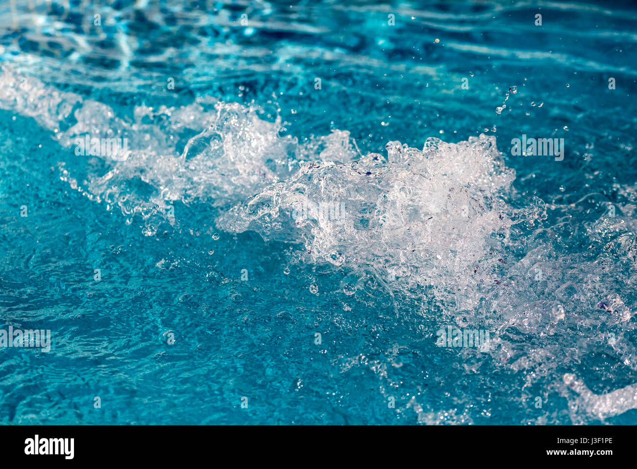 Close-up of a inflowing water jet into a swimming pool with blue floor ...