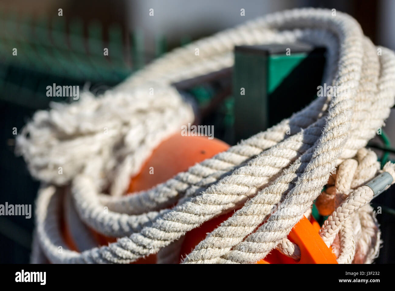 White rope tied to orange float used by lifeguards at swimming pool or ...