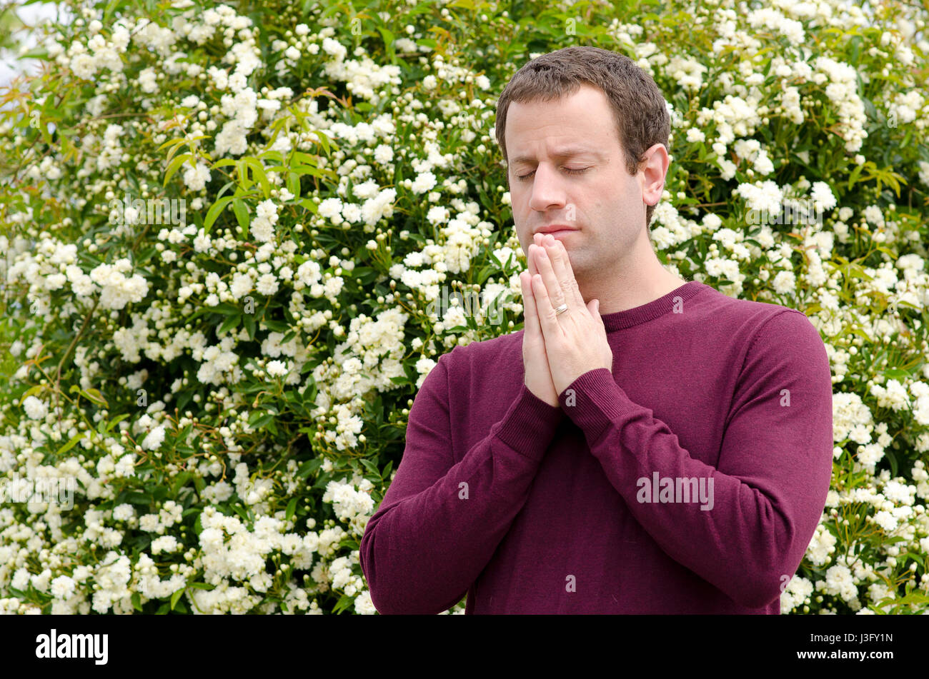Side profile of man praying in front of a flowering bush Stock Photo ...