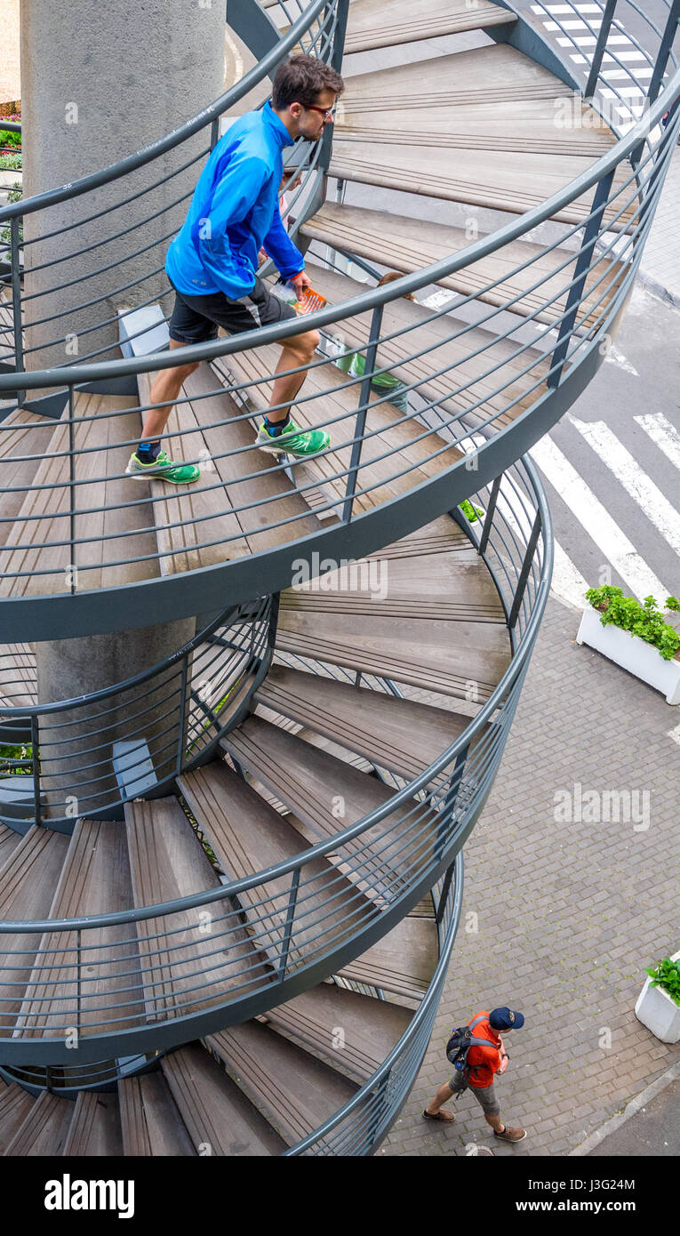Man climbig a metal spilar stair case Stock Photo - Alamy