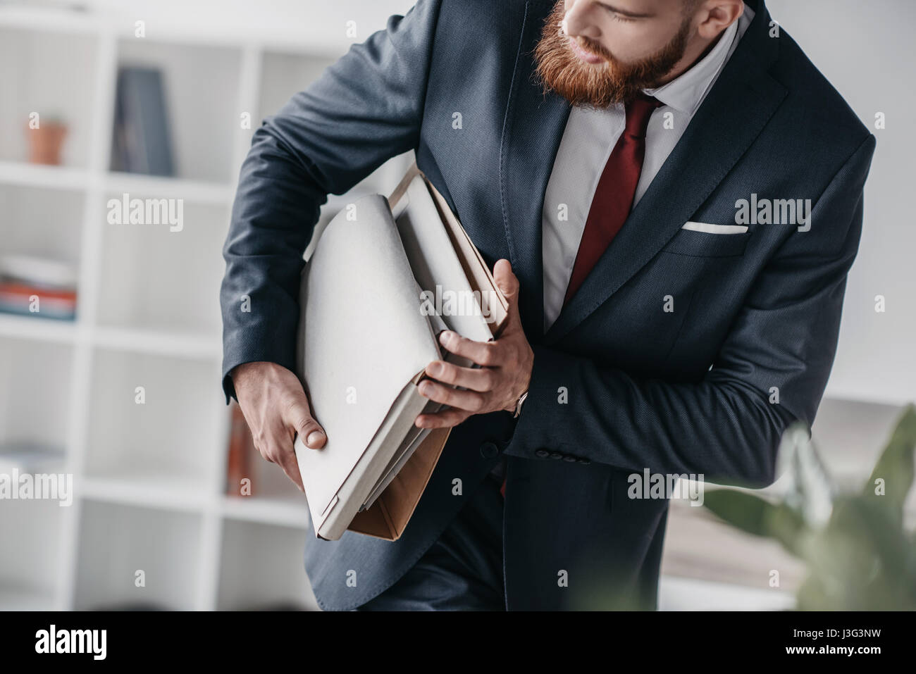young businessman in suit holding documents and folders in office Stock ...