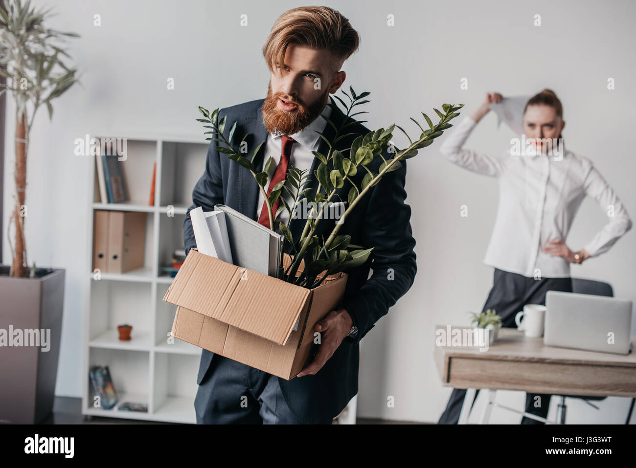 Young upset fired businessman with cardboard box in office, angry boss ...