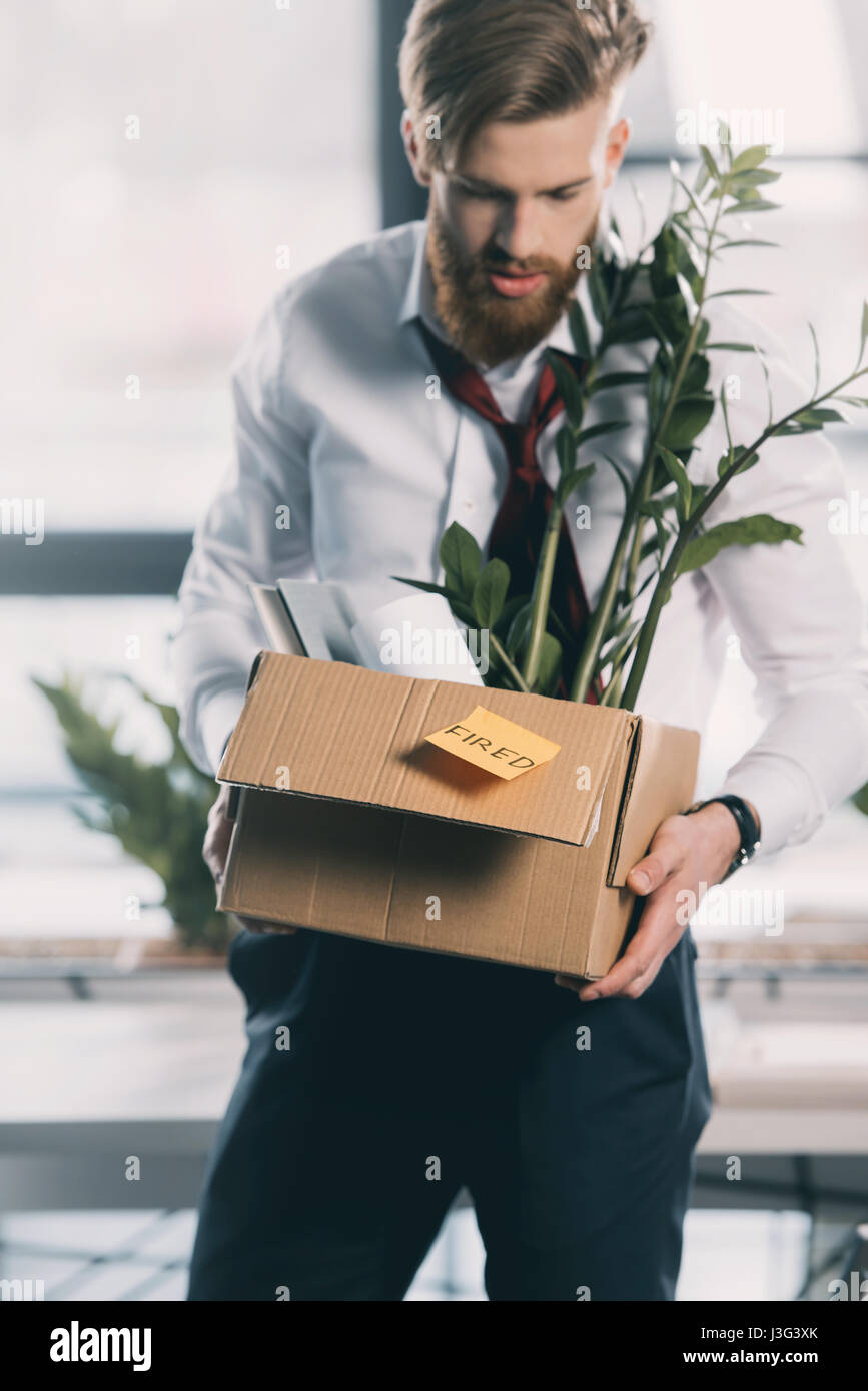 Young upset fired businessman with cardboard box in office Stock Photo ...