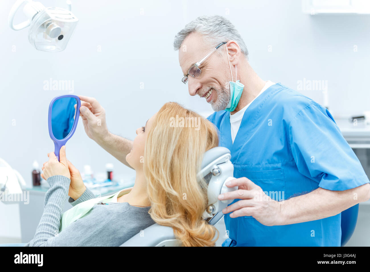 senior dentist in uniform talking with patient in dental clinic Stock ...