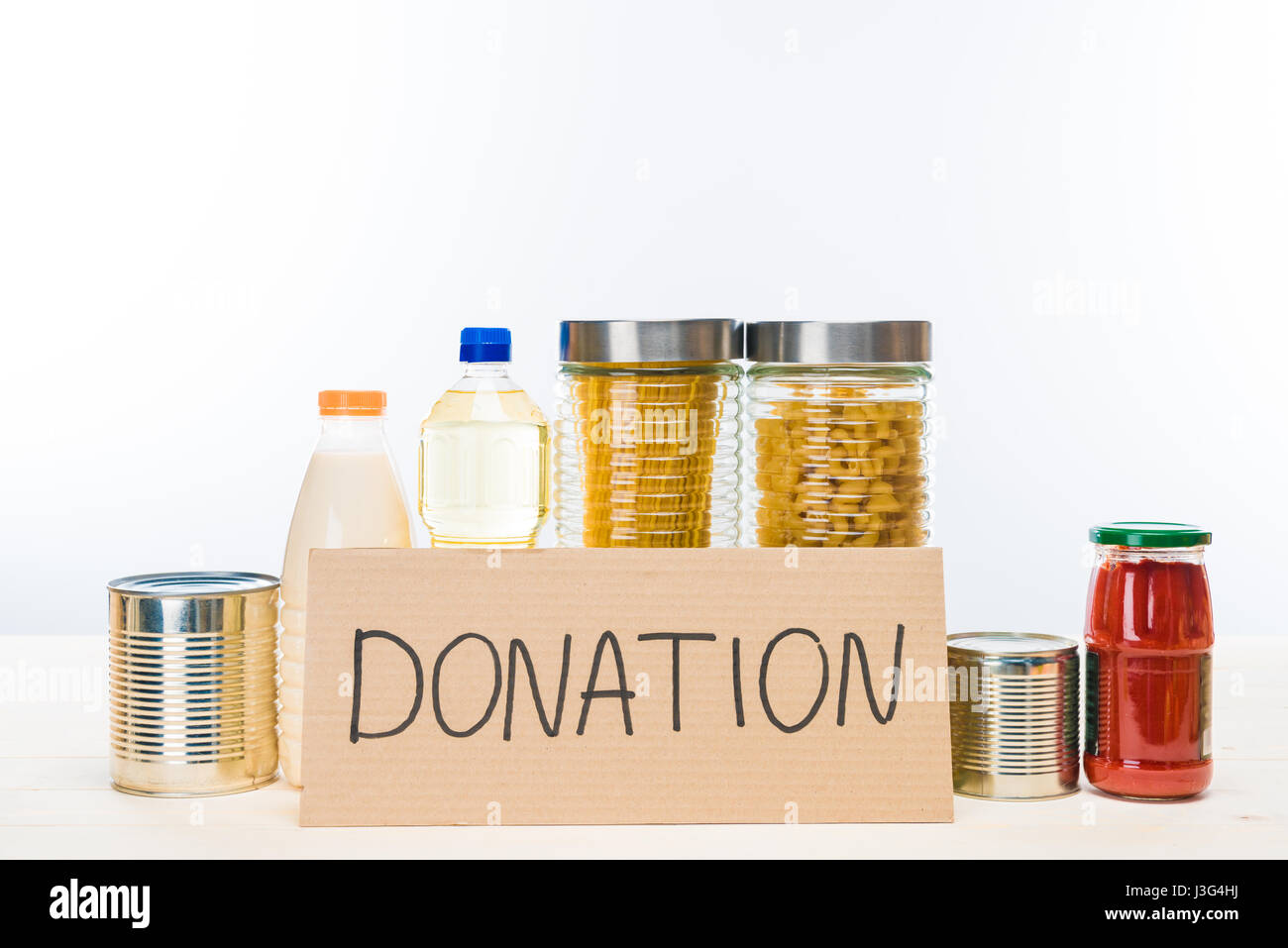 different food with cardboard donation sign on wooden table on white ...
