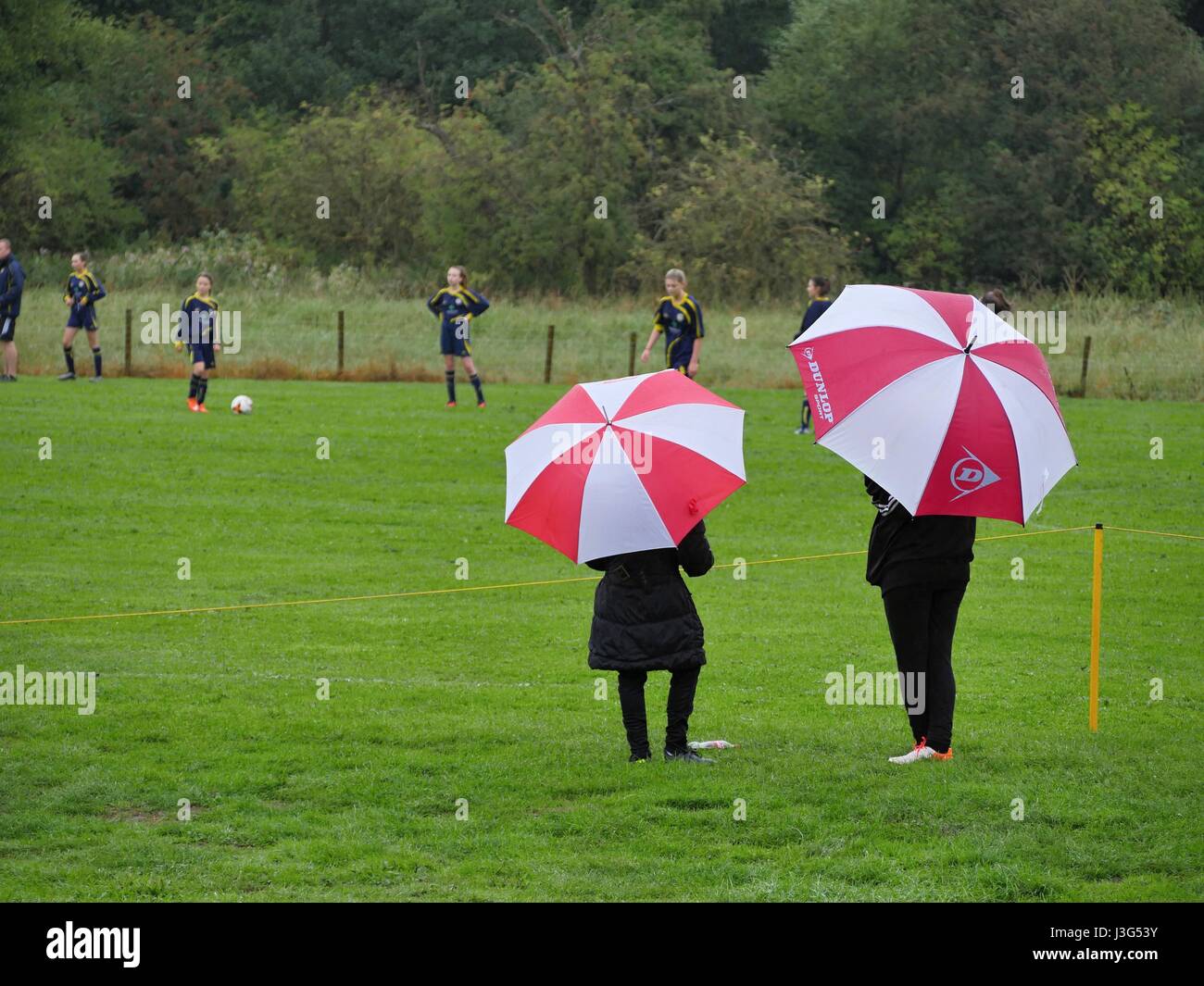 People watching girls football match in the rain Stock Photo - Alamy