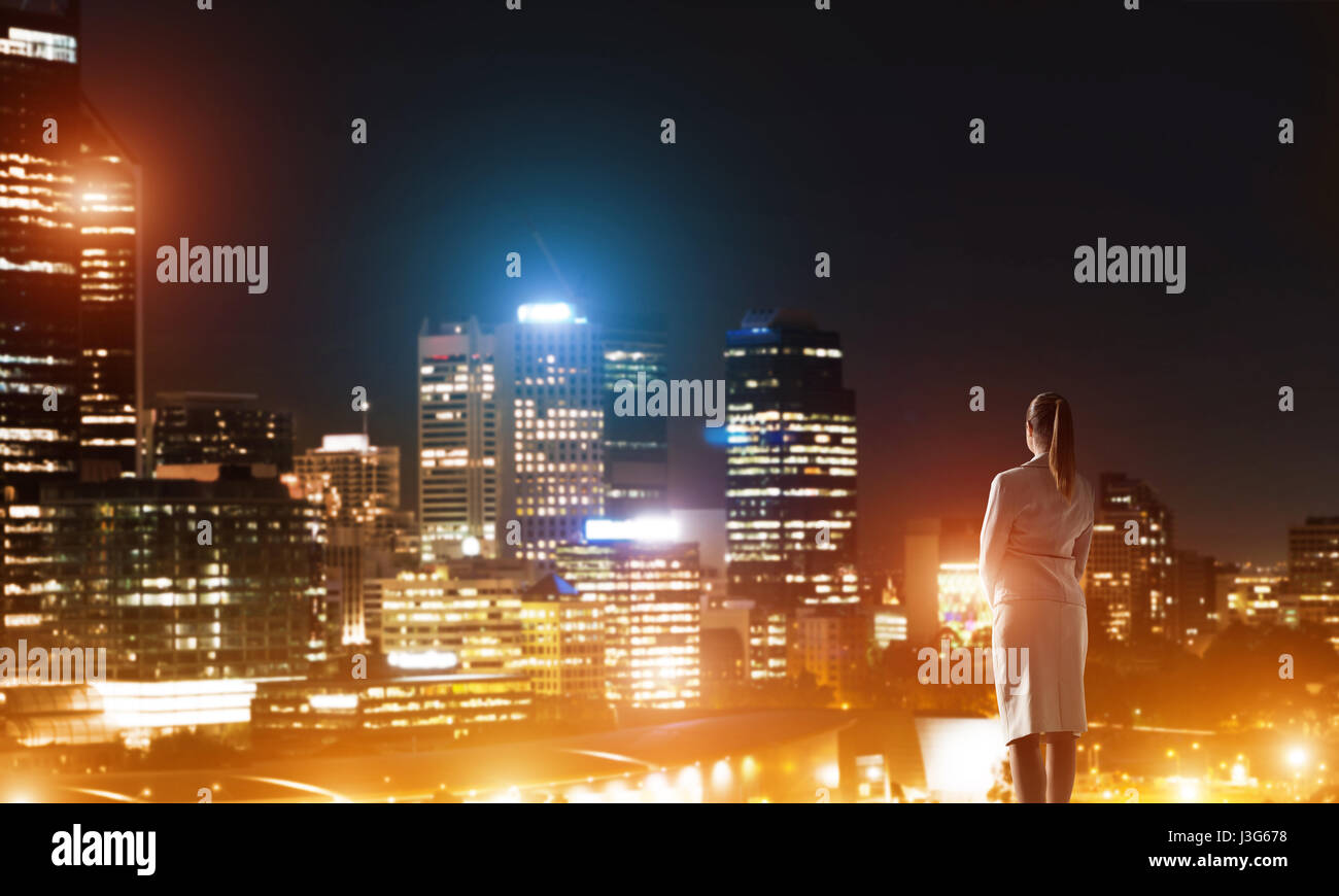 Rear view of elegant businesswoman viewing lights of night city Stock ...