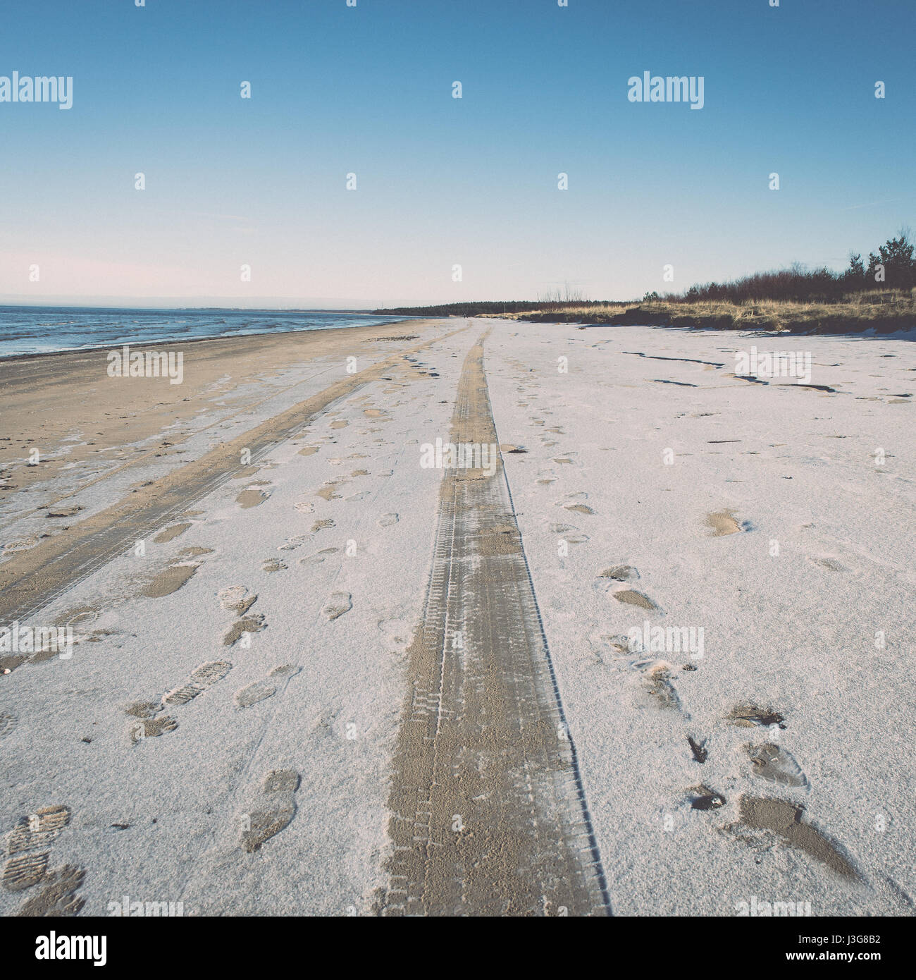 frozen sea beach with blue sky and snow covered tracks - retro vintage ...