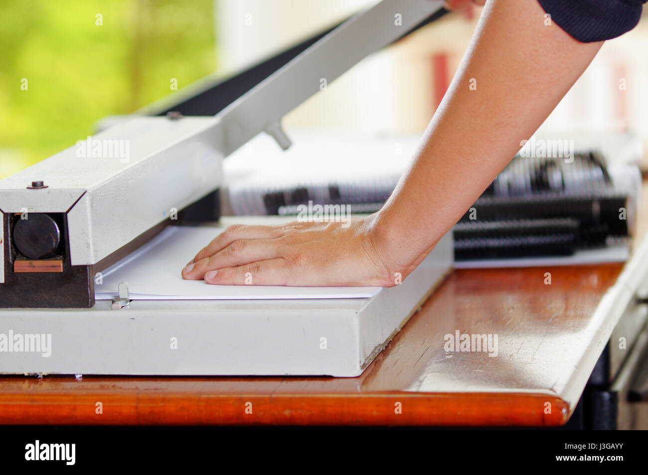 Man using manual paper cutter to cut the bills printed in the sheets of ...