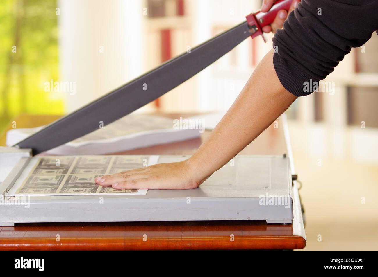 Man using manual paper cutter to cut the bills printed in the sheets of ...