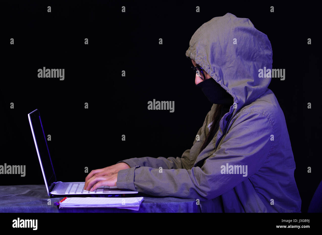 Portrait of a beautiful and smart girl hacker with laptop on dark ...