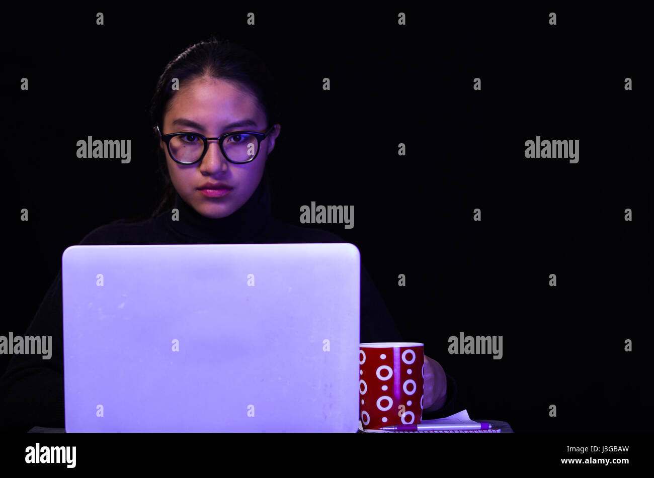 Portrait of a beautiful and smart girl hacker with laptop on dark ...