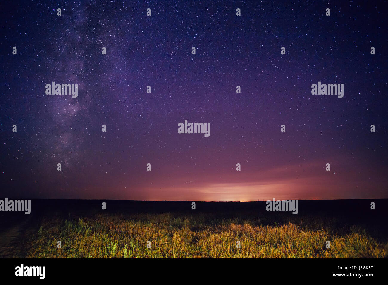 Blue Night Starry Sky Above Field And Yellow City Lights On Background ...