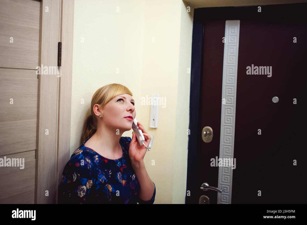 blonde woman answers the intercom call, hold the phone to his ear ...