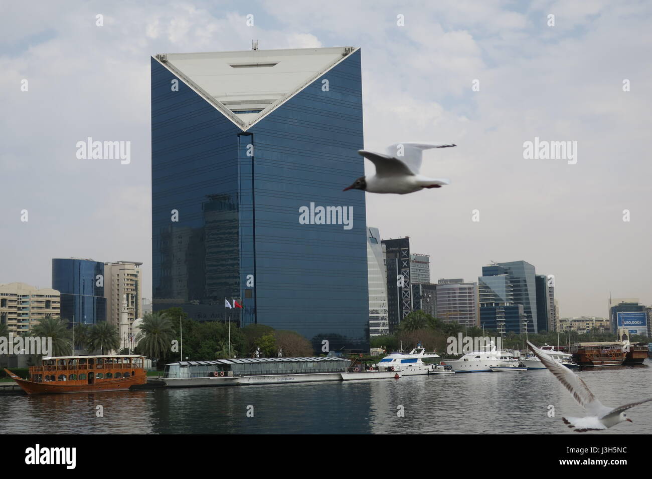 Lots of ships on a sea canal in Dubai. A view at famous skyscrapers ...